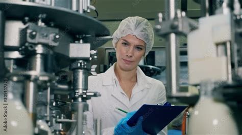 A Woman Checks Bottles With Milk Moving On A Conveyor Quality Control Of Production Line At A