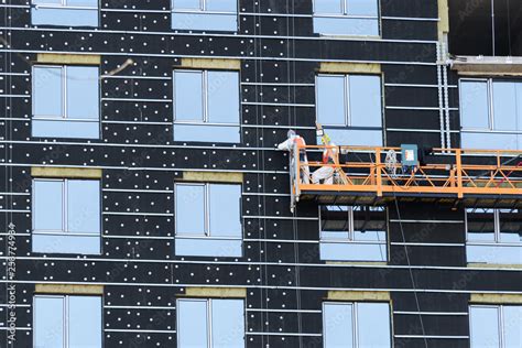 Construction Winch With Workers On A Concrete Wall Of A High Rise