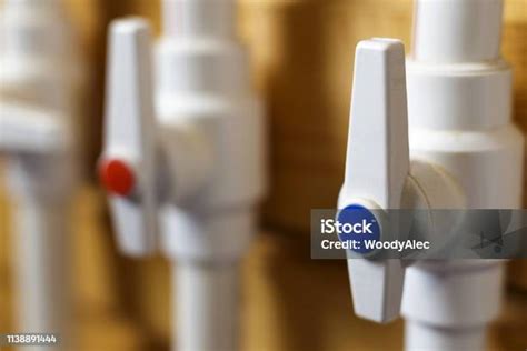 나무 벽에 레버 손잡이가 있는 뜨거운 물과 차가운 물을 위한 두 개의 흰색 폴 리 프로필 렌 파이프 볼 밸브의 선택적 초점으로