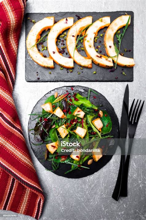 따뜻한 Arugula의 혼합 잎 호박 샐러드 Chard 회색 바탕에 검은 슬레이트 접시에 구운된 호박입니다 상위 뷰 0명에 대한