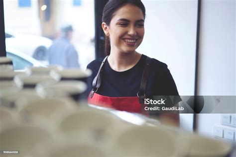 자동 기계 장비를 사용 하 여 방문자에 대 한 우수한 커피를 만들고 카페테리아에서 작업 과정을 즐기는 매력적인 웃는 여성 바리