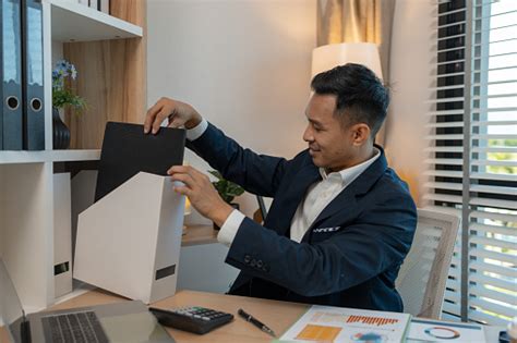 흰 셔츠와 양복을 입은 중년의 전문직 사업가가 사무실에서 행복한 미소를 짓고 있고 양복을 입은 검은 머리의 중년 사업가가 사무실 책상에서 행복하게 일하고 있습니다 20 24