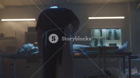Pathologist Conducting Post Mortem Examination On Cadaver In The Morgue