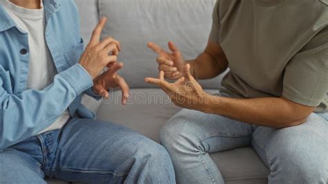 Two Men Sitting Together And Using Sign Language Highlighting A Loving Relationship In A Living