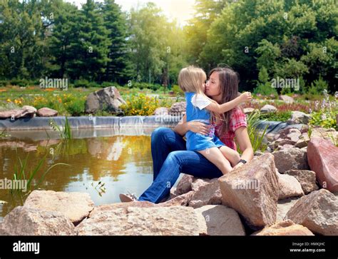 Mom And Daughter Are Sitting Near A Pond In The Park Stock Photo Alamy
