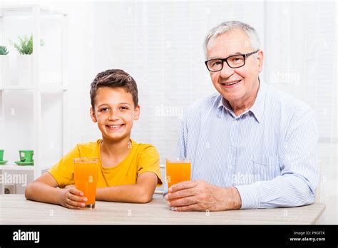Grandfather And Grandson Are Drinking Orange Juice At Home Healthy Lifestyle Stock Photo Alamy