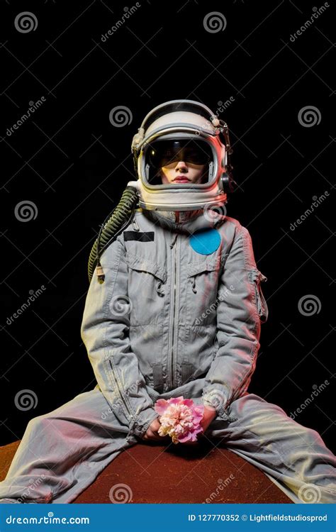 Astronauta De Sexo Femenino En Spacesuit Y Casco Que Se Sienta En El Planeta Con La Flor Foto De