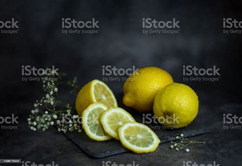 어두운 배경에 흰색 꽃이 있는 테이블에 전체 레몬과 얇게 썬 레몬 조각으로 구성된 우아한 겨울 정물 0명에 대한 스톡 사진 및