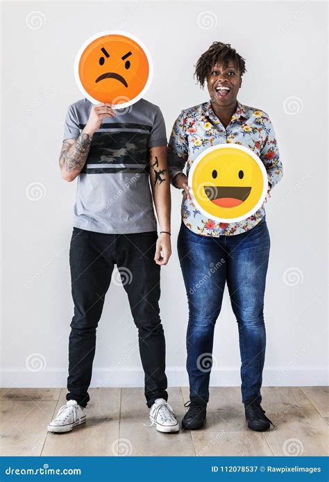 Interracial Couple Holding An Expressive Emoticon Face Facial Expression Frown And Smile