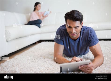 Man Using A Tablet Computer While His Girlfriend Is Reading A Book Stock Photo Alamy