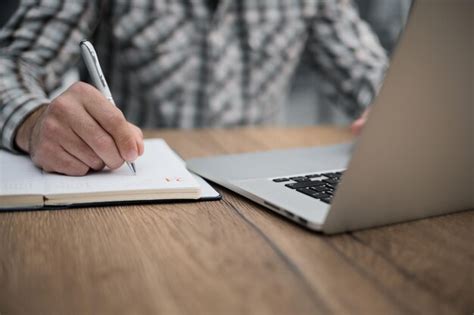 Premium Photo Hands Writes A Pen In A Notebook Computer Keyboard In Background