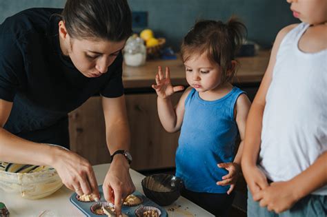 어린 아이들과 함께 부엌에서 컵케이크 실리콘 몰드에 반죽을 채우는 어머니 과자 요리의 개념입니다 머핀 파이 비스킷을 만드는 단계 단계별로 베이킹 과정 2 3 살에 대한 스톡