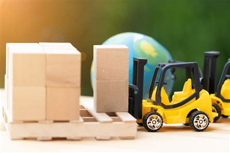 미니 지게차 트럭은 자연 배경과 지구와 나무 팔레트에 골판지 상자의 스택을로드합니다 물류 및 운송 관리 아이디어 및 산업