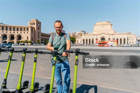 아르메니아 예레반의 공화국 광장에서 스마트 폰을 사용하여 전기 스쿠터를 임대하는 중년 남성 Brand Name Mobile