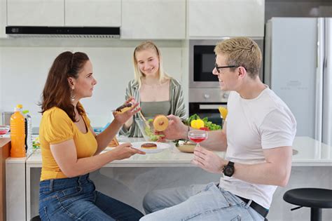 다양한 연령대의 행복한 가족이나 친구들이 집의 부엌에서 샐러드 도누스 과일 청량 음료와 함께 아침 식사 또는 디저트를 먹는 것을 즐깁니다 행복과 건강한 라이프스타일 개념