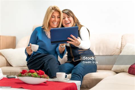 거실에서 소파에 앉아 디지털 태블릿 스톡 사진을 사용하는 두 성인 쾌활한 여자 2명에 대한 스톡 사진 및 기타 이미지 2명 40 49세 가정 생활 Istock