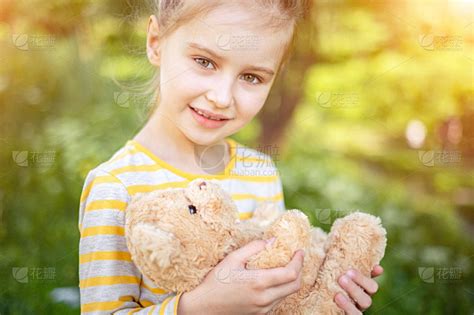 小女孩带着泰迪熊在公园里