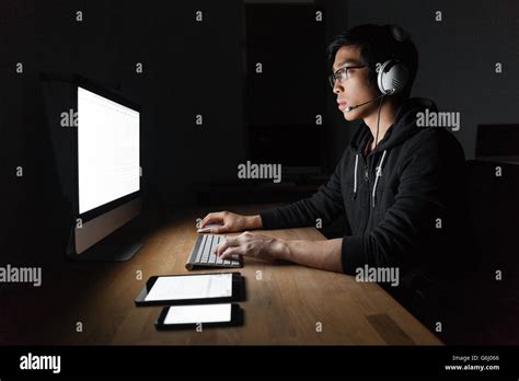 Man In Headphones Using Blank Screen Computer Tablet And Mobile Phone In Dark Room Stock Photo