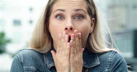 충격받은 여성이 얼굴을 만지고 도시에서 손으로 입을 가리는 클로즈업 초상화 무서워하고 불안하고 공황 상태에 빠진 젊은 아름다운 여성 와우 표정으로 밖에 홀로 서 있는 여자