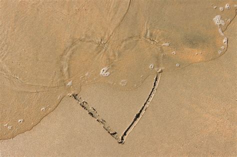 햇볕이 잘 드는 해변에 막대기로 모래 해변의 젖은 황금빛 모래 물가의 파도 해변 해안선 고감도 복사 공간 그린 하트 모양의 전체 프레임 이미지 0명에 대한 스톡 사진 및