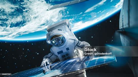 우주 공간에서 정기 유지 보수 점검을 위해 우주선 외부에서 태양 전기 패널을 수리하는 전문 우주 비행사 우주 기술 지속 가능한 에너지 및 탐사 개념 경관에 대한 스톡 사진