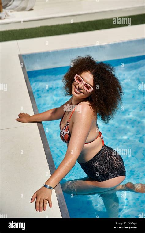 A Woman With Curly Hair Enjoys A Summer Day By The Pool Wearing A