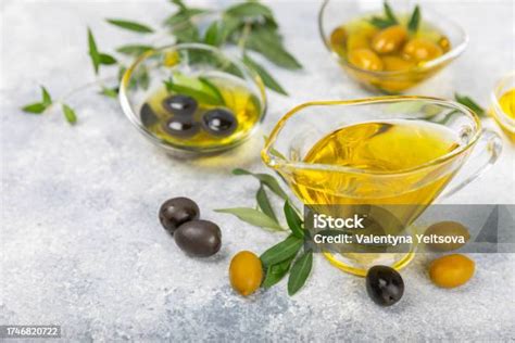 유리 그릇에 담긴 올리브 오일 그레이비 보트 질감이 있는 식탁에 담긴 병 올리브의 가지와 열매가 달린 기름 병 텍스트를 위한