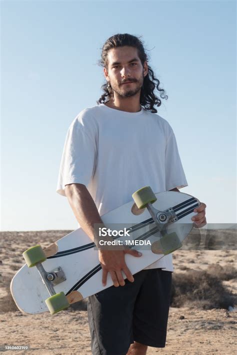 그의 스케이트 보드를 들고 야외에서 서 젊은 성인 스케이터 초상화 검정 머리에 대한 스톡 사진 및 기타 이미지 검정 머리