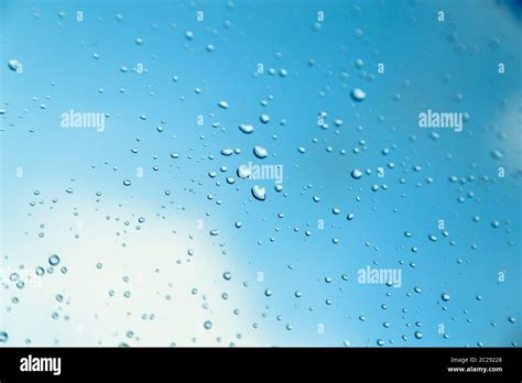 Water Drops On The Window Blue Sky And Clouds In The Blurry Background