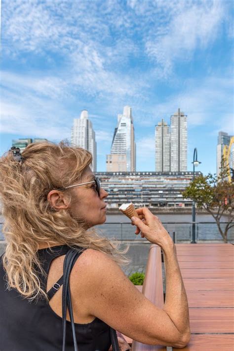 Adult Blonde Woman Having An Ice Cream With The Buildings Of Puerto