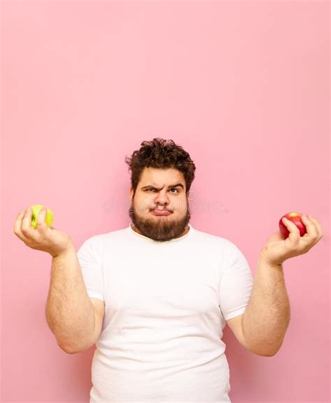 Overweight Funny Guy Stands With Apples In His Hands On A Pink