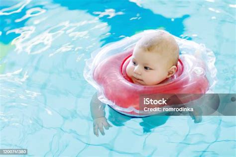 실내 수영장에서 수영 링으로 수영을 배우는 귀여운 어린 아기 신생아 소녀 또는 소년 물에서 재미 아기와 어린이를위한 적극적인 건강한 레저 및 스포츠 신생아에 대한 스톡 사진