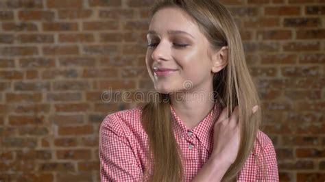 Young Beautiful Girl Touches Her Hair Moves Watching At Camera Brick