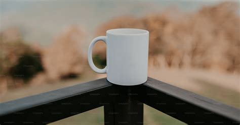 나무 난간 위에 앉아 있는 하얀 커피잔 사진 Unsplash의 컵 이미지