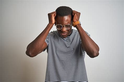 스트라이프 티셔츠와 안경을 착용한 아프리카계 미국인 남성이 두통을 앓고 있는 고립된 흰색 배경 위에 통증과 편두통때문에 스트레스를 받았다 머리에 손을 T 셔츠에 대한 스톡