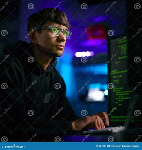 Low Key Lighting Shot Of Male Computer Hacker Sitting In Front Of