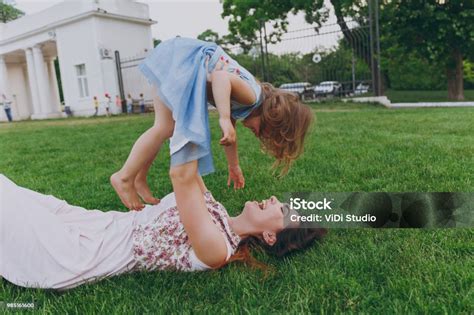 빛 드레스에 즐거운 여자 녹색 잔디 나머지에 거짓말을 작은 귀여운 아이 아가 발생 재생 하 고 재미 어머니 딸 아이입니다