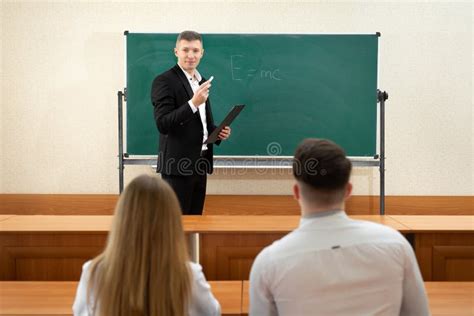 Teacher Giving A Lecture In A Classroom And Writing Math Formulas On