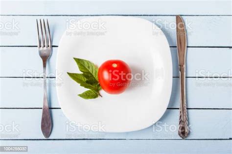 신선한 유기농 토마토 고 흰 접시에 토마토 잎 포크와 나이프 나무 테이블에 건강 식품 개념입니다 상위 뷰 0명에 대한 스톡 사진 및 기타 이미지 Istock
