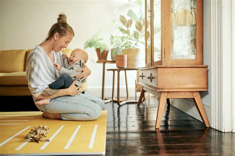 어머니는 미소 짓고 아기와 집 거실에서 놀고 유대감을 형성하고 함께 즐거운 시간을 보냅니다 발달 행복 및 엄마는 아이 아이 또는 신생아를 안고 집에서 양질의 시간을 즐기면서