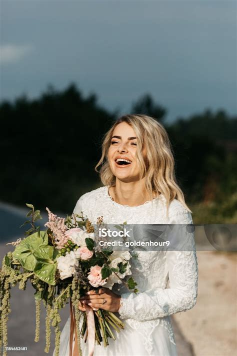 긴 전체 스커트와 긴 소매 레이스 웨딩 드레스에 아름다운 우아한 신부 그녀는 꽃의 큰 꽃다발을 들고있다 자연 배경에 도시와 Bridal Show에 대한 스톡 사진 및 기타