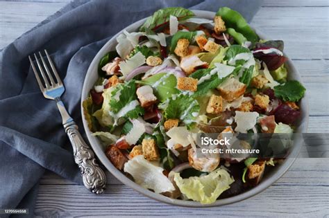 그릇에 치킨 시저 샐러드의 이미지 양상추 붉은 양파 비트 뿌리 잎 큐브 베이컨 구운 닭고기 크루통과 파마산 치즈 면도 회색 차 타월과 금속 포크 나무 곡물 배경 높은 전망