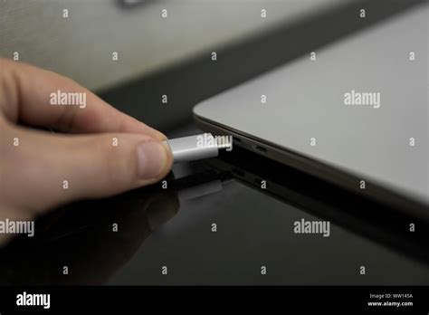 Male Hand Plugging White USB C Type C Cable Into A Port On A Grey Laptop Notebook Computer USB