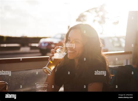 Positive Young Female In Casual Clothes Smiling And Drinking Cold Beer