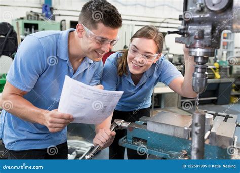 Engineer Instructing Female Apprentice On Use Of Drill Stock Image