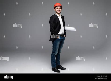 Young Male Architect Wearing Helmet And Holding Blueprints Isolated On White Background Stock
