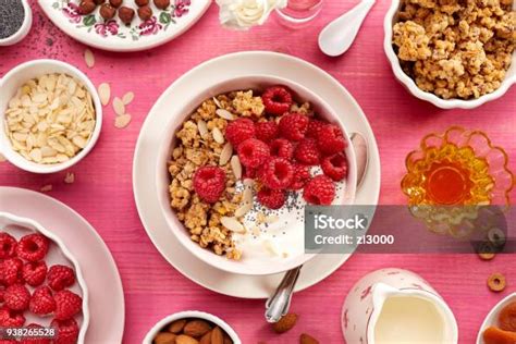 그 라 놀라와 천연 요구르트 신선한 나무 딸기 꿀 아몬드 플레이크 분홍색 나무 테이블 평면도에 세라믹 그릇에 양 귀 비 씨앗 맛있고 영양가 있는 아침 식사 또는 디저트입니다