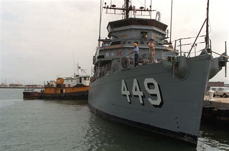 A Tug Boat Moves In To Guide The Ocean Minesweeper Uss Impervious Mso 449 Away From The Pier