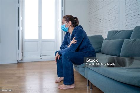 집에서 소파에 우울 보호 얼굴 마스크를 가진 슬픈 아픈 라틴어 여자 코로나바이러스 사망 잠금 및 사회적 불변속에서 피곤하고 걱정스러운 우울증을 느끼는 절망적 인 여성 정신