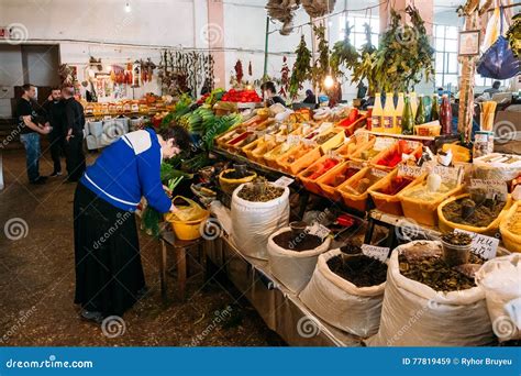 Elderly Georgian Woman Seller Sorting Herbs Near Abundant Counte